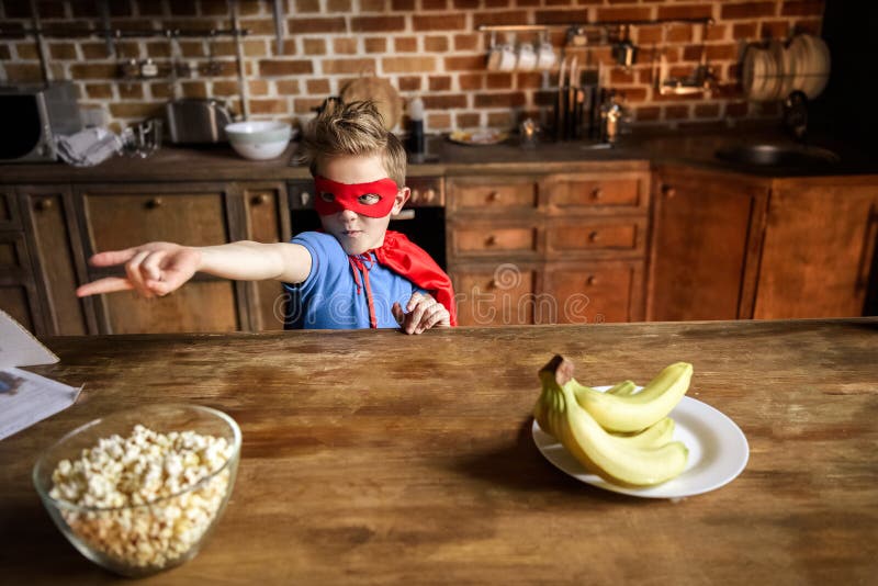 Boy in Red Superhero Costume Sitting in Kitchen and Playing Stock Image ...