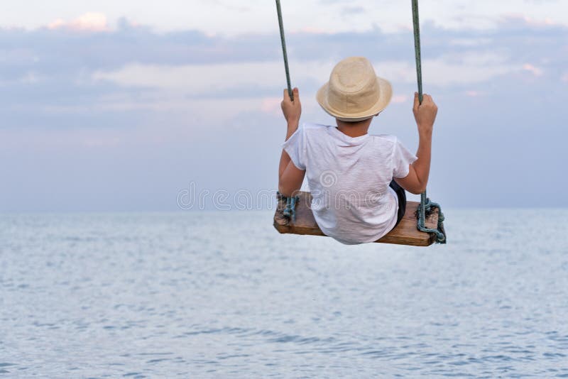 Boy Rides on a Swing Over the Water Back View. Vertical Frame Stock ...