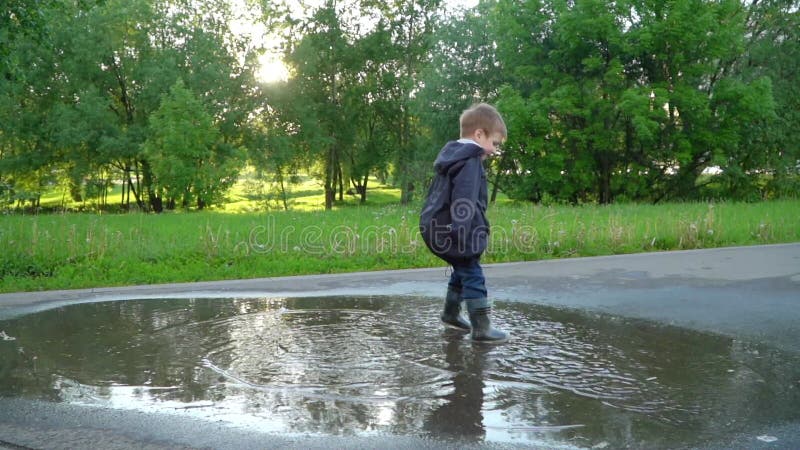 Boy in Rubber Boots Jumping in a Puddle Stock Footage - Video of ...
