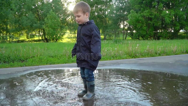 Boy in Rubber Boots Jumping in a Puddle Stock Footage - Video of ...