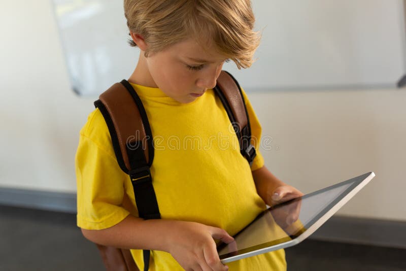 Boy with School Bag Using Digital Tablet in a Classroom Stock Image ...