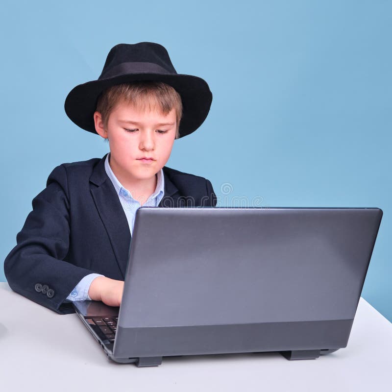 A Boy in a School Suit with a Sheet of A4 Paper at a Computer during ...