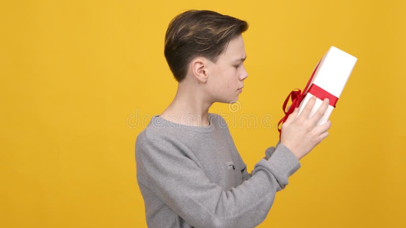 Boy Shaking Wrapped Gift and Hugging Present Box, Yellow Background ...