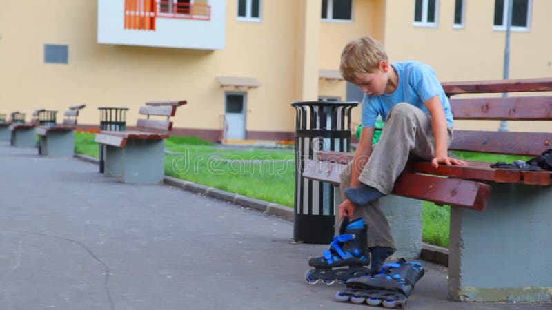 Boy Sits on Bench in Foreyard and Puts on Roller Stock Video - Video of ...