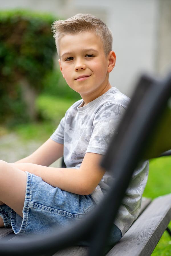 A Boy Sits on a Park Bench and Looks Directly at the Camera Stock Photo ...