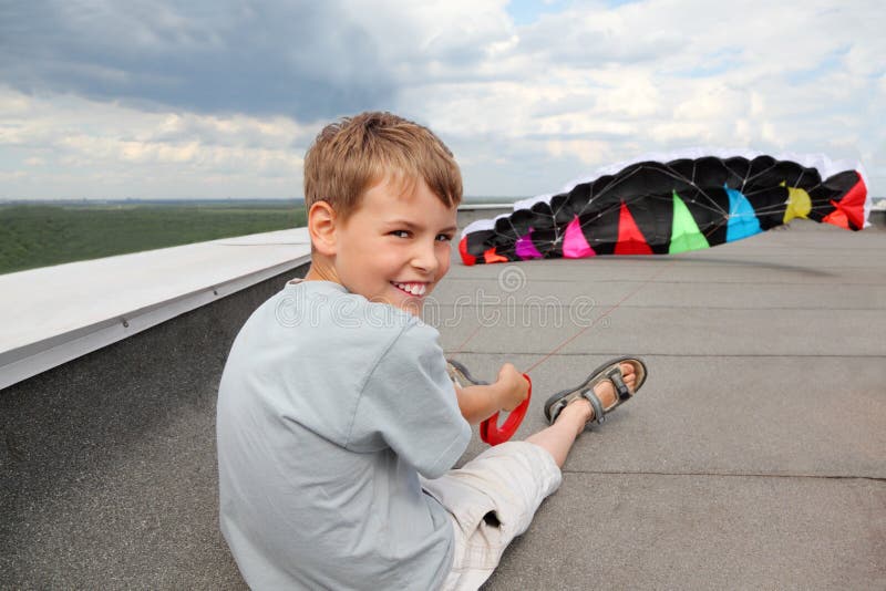 Boy Sits on Roof of House, Holds Parachute Stock Photo - Image of happy ...