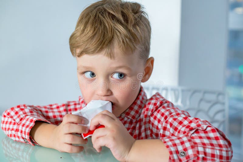 Boy Sits at the Table and Eats a Chocolate Bar. Stock Image - Image of ...