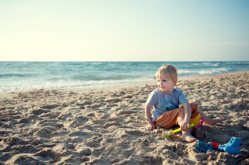 Boy sitting on a beach stock image. Image of small, hand - 27409611