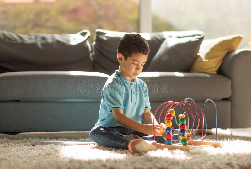 Boy Sitting on a Carpet at Home and Playing with a Logic Toy Stock ...