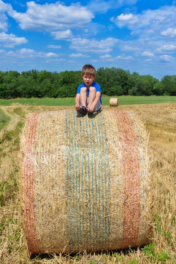 The Boy is Sitting on Golden Hay Bales on the Field Stock Photo - Image ...