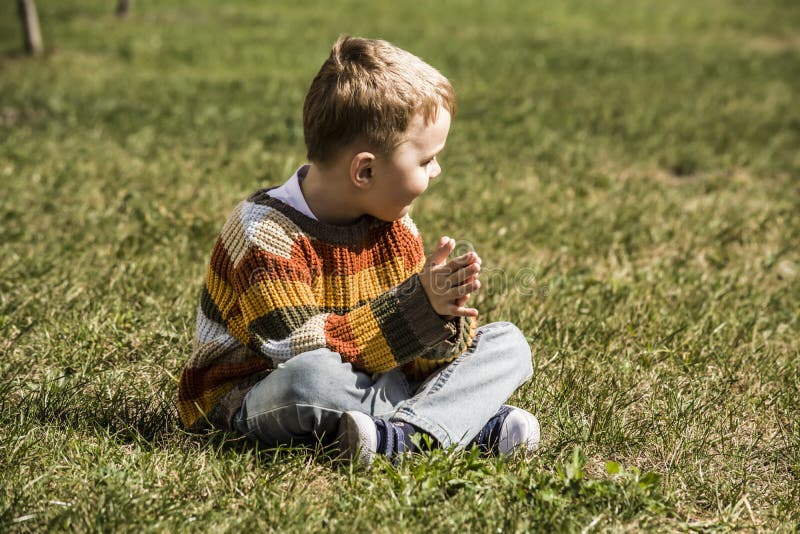 Boy sitting on the grass stock image. Image of sweater - 59706575