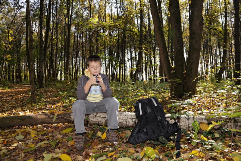 Boy Sitting on Log with Cup Stock Photo - Image of horizontal, casual ...