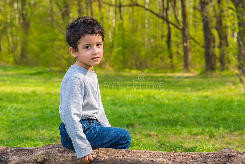 Boy Sitting on a Log in Forest Stock Photo - Image of sitting, natural ...