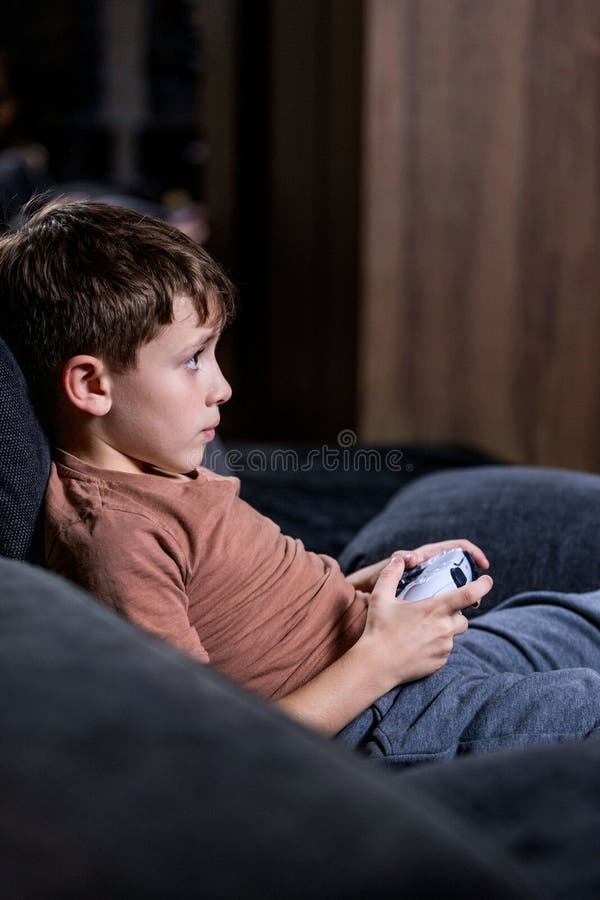 Boy is Sitting on Sofa at Home and Playing Video Games with His Joypad ...