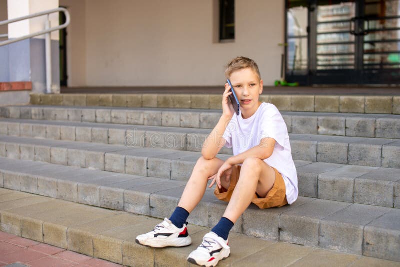 The Boy is Sitting on the Steps and Talking on the Phone Stock Image ...