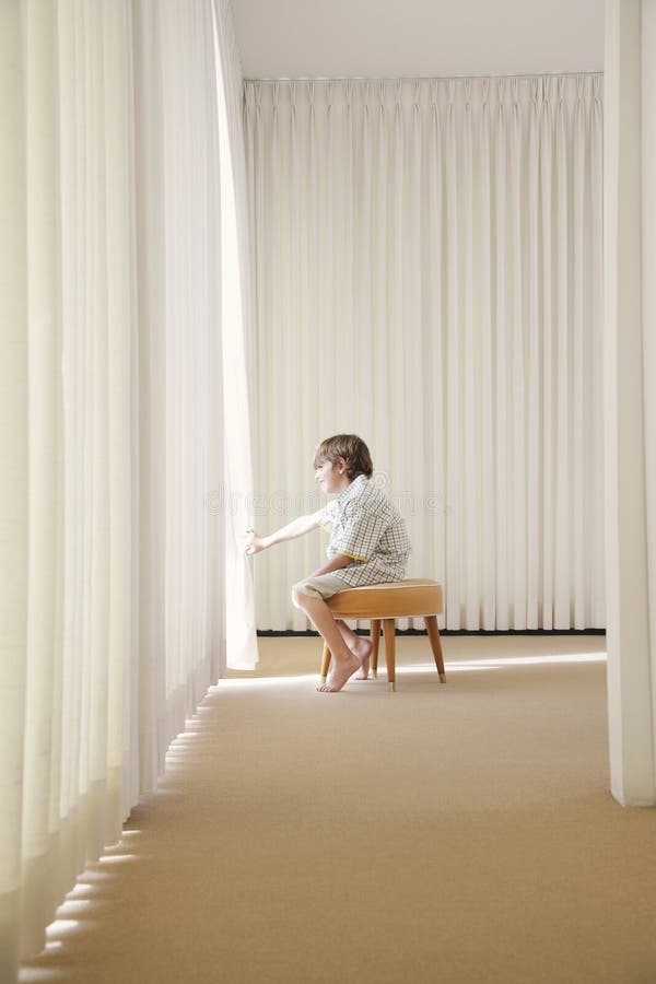 Boy Sitting on Stool Looking Out Window Stock Image - Image of indoors ...