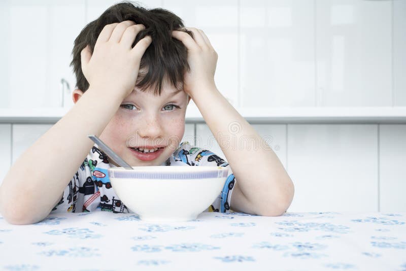 Boy (5-6) Sitting at Table with Bowl in Front of Face Stock Photo ...