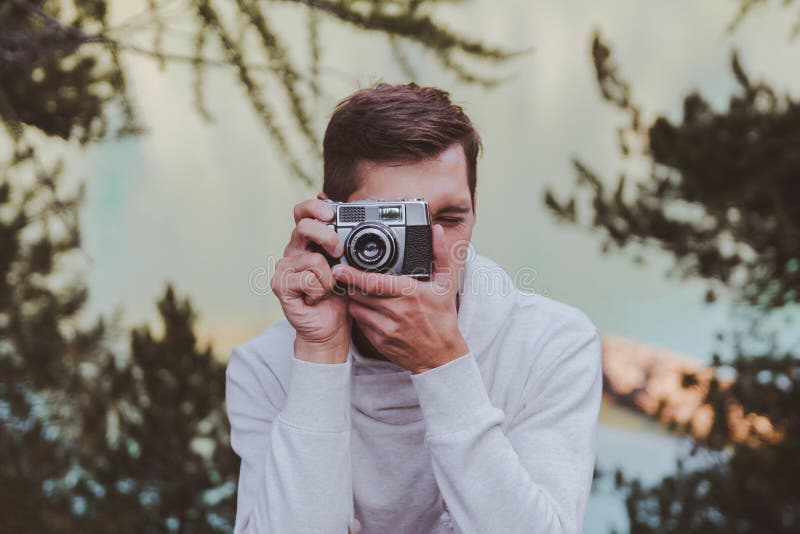 Young Man Using a Vintage Camera in Front of a Turquoise Lake Stock ...