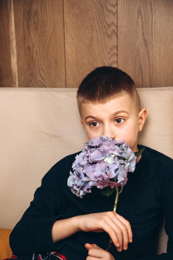 The Boy Sniffs a Purple Hydrangea Holding in His Hands Against the ...