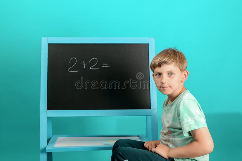 The Boy Solves the Math Equation 2 + 2 Written on the Blackboard. the ...