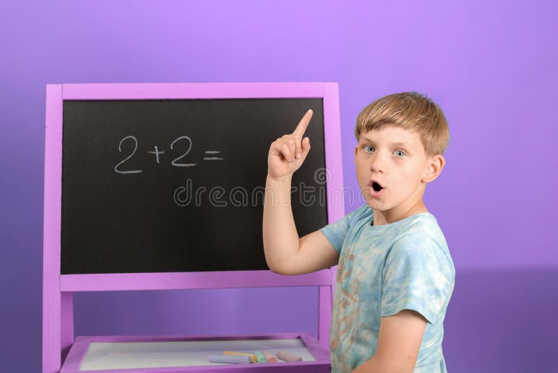 The Boy Solves the Math Equation 2 + 2 Written on the Blackboard. the ...