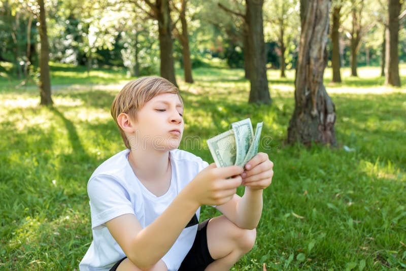 The Boy is Squatting in the Park, Counting Banknotes and Grimacing ...