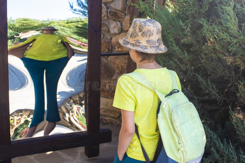The Boy Stands in Front of a Distorting Mirror. Stock Image - Image of ...
