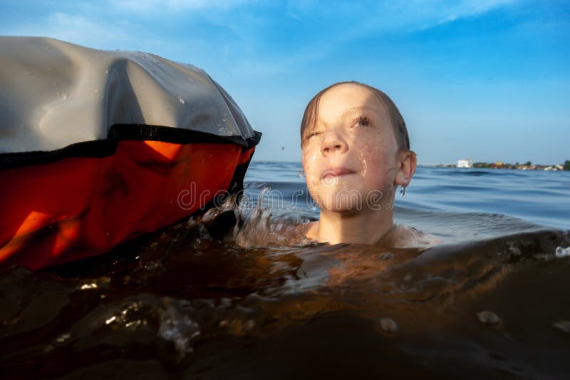 The Boy Swims in the Water with the Help of an Inflatable Ring Stock ...