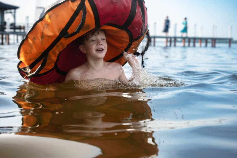 The Boy Swims in the Water with the Help of an Inflatable Ring Stock ...