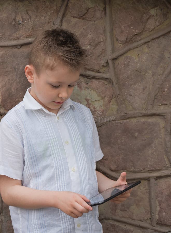Boy with Tablet Near School with a Book Online Learning Boy Looking at ...
