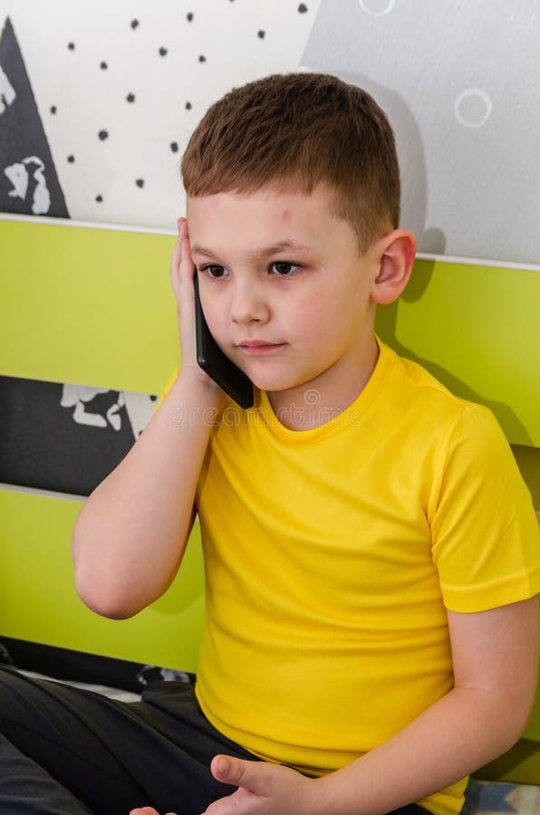 The Boy is Talking on the Phone while Sitting on His Bed in His Room ...
