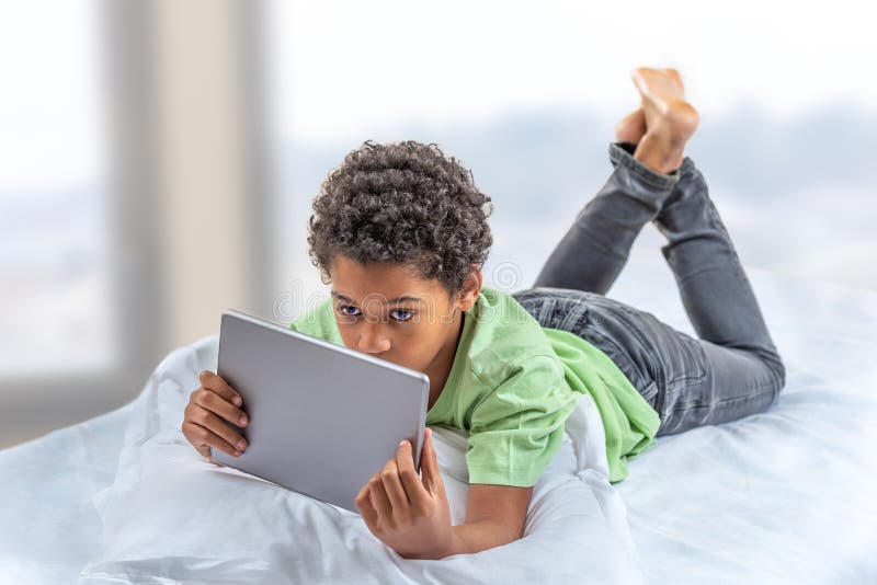 Boy Teenager with Tablet Computer Lying in Bed Having Fun in Bedrom ...