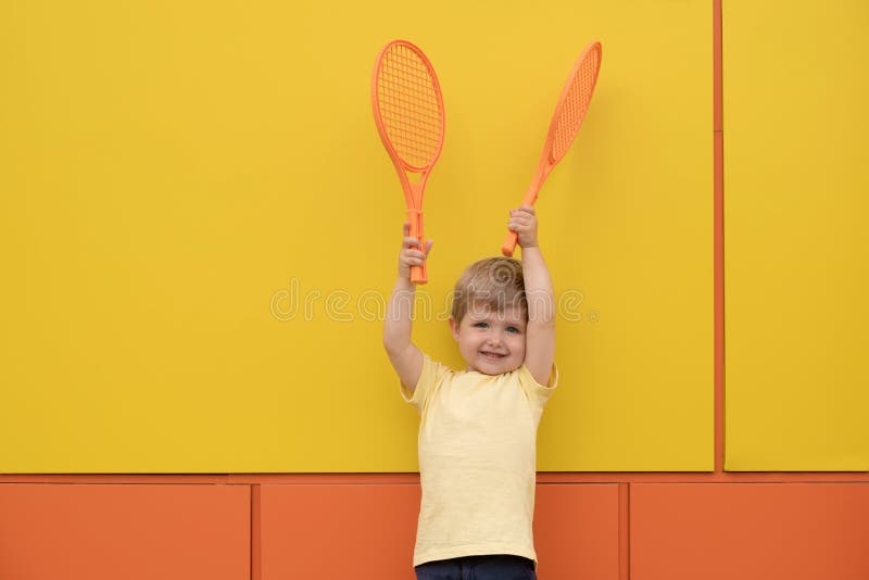 Boy with Tennis Rackets Against Yellow Wall Stock Photo - Image of ball ...