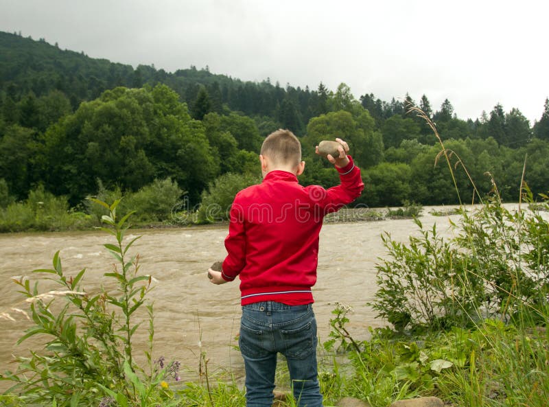 Boy Throw Stones in the River. Boy in Red Jacket Throws Stones Stock ...