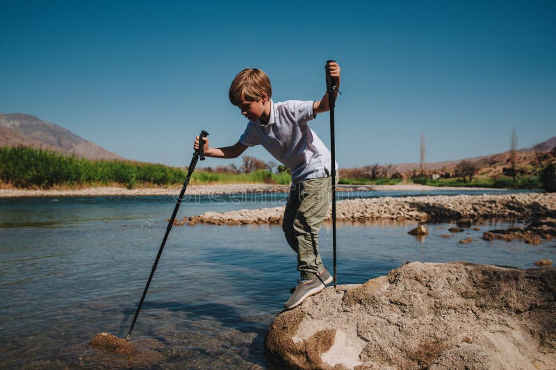Boy with Trekking Poles Checks the Depth of Mountain River Stock Photo ...