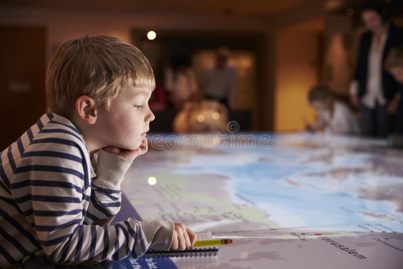 Boy on Trip To Museum Looking at Map and Writing in Notebook Stock ...