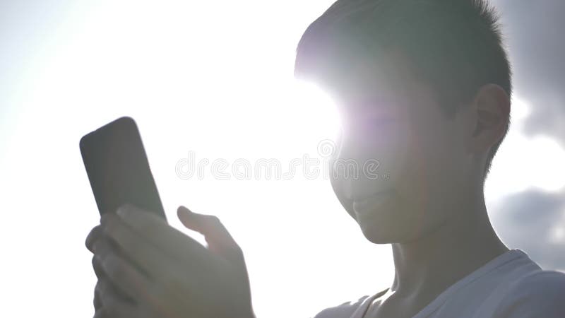 Boy Uses a Phone Outdoors, Moving Camera Stock Footage - Video of light ...