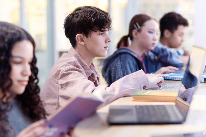 Boy Using Computer in Library with Students in Row Stock Photo - Image ...