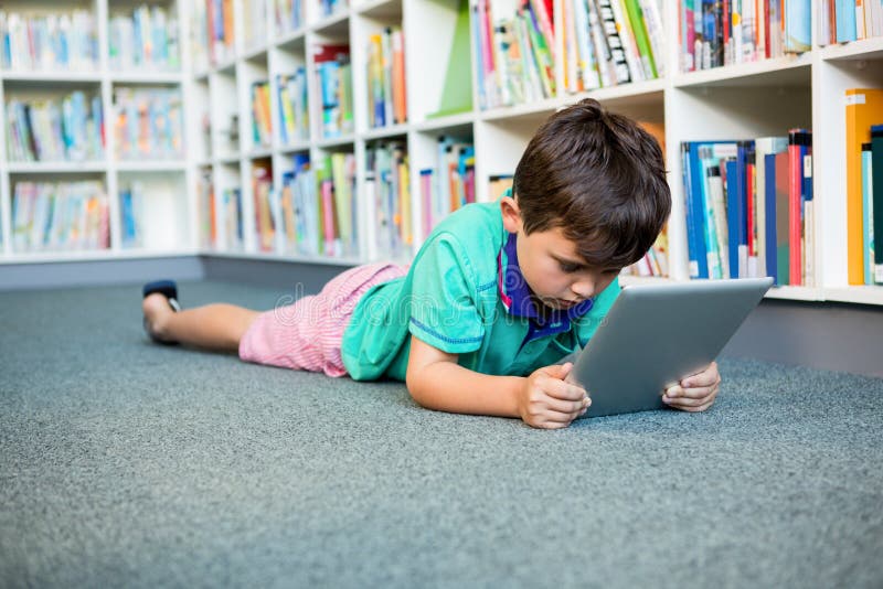 Boy Using Digital Tablet in School Library Stock Photo - Image of lying ...