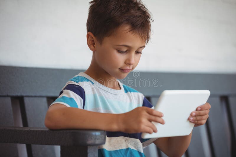 Boy Using Digital Tablet while Sitting on Bench Stock Image - Image of ...