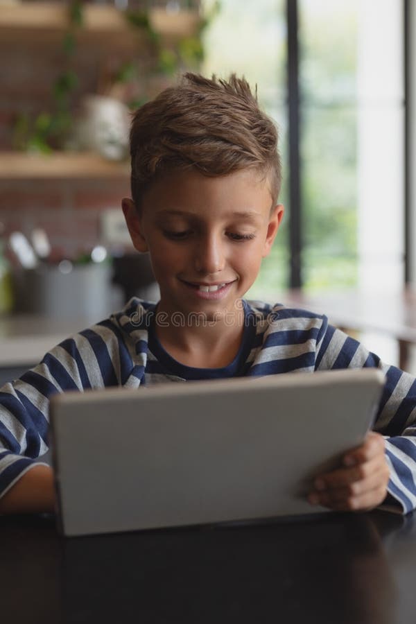 Young Boy Using Tablet Computer at Kitchen Table, Front View Stock ...