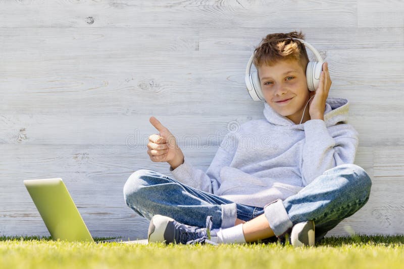 A Boy Using a Laptop and Headphones Outdoors Stock Image - Image of ...