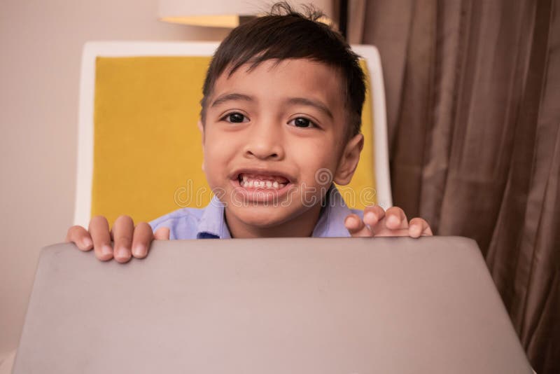 An Asian Hijab Mother is Working from Home Using a Laptop Stock Photo ...