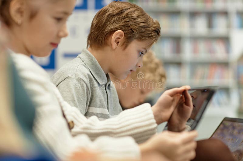 Boy Using Laptop in Library with Children in Row Stock Image - Image of ...