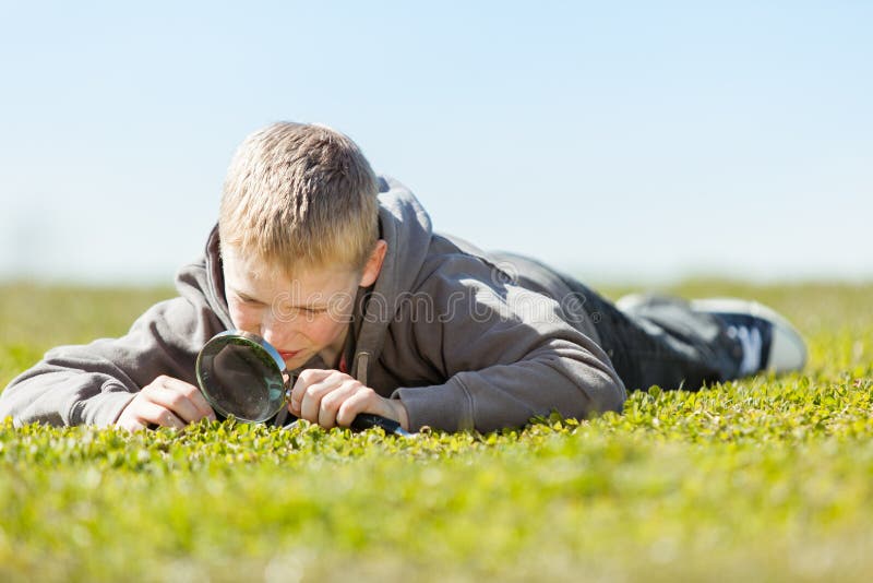 Boy Using Magnifying Glass Over Field of Grass Stock Photo - Image of ...