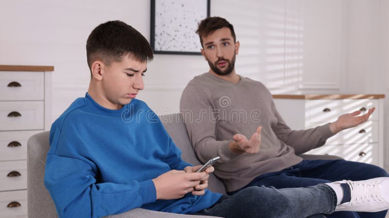 Boy Using Smartphone and Ignoring His Upset Father at Home. Teenager ...