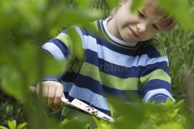 Boy Using Trowel in Garden stock image. Image of focused - 33899639