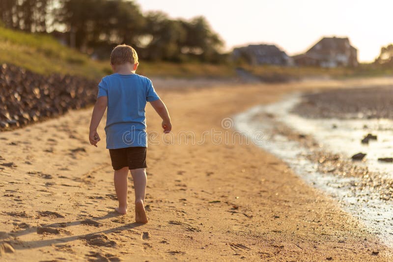 Boy Walking Barefoot on a Sandy Beach at Sunset Stock Image - Image of ...