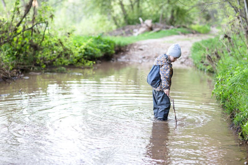 Boy walking in the forest stock photo. Image of puddle - 80657502