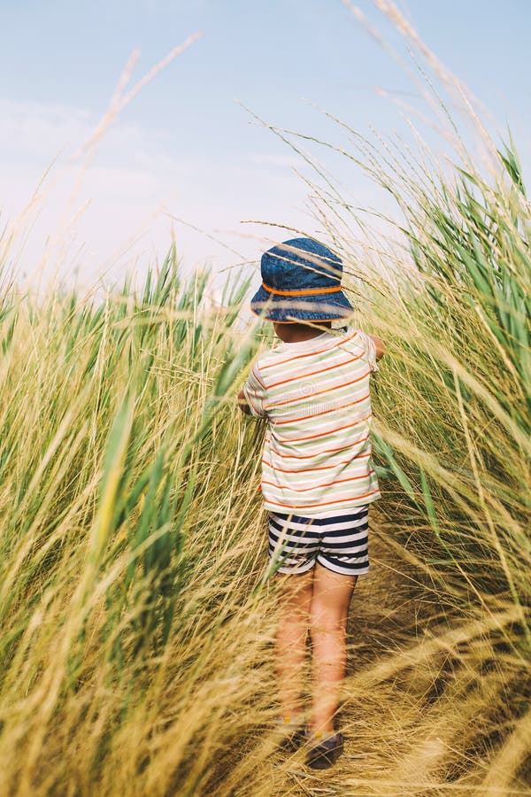 Boy walking hrough grass stock photo. Image of grass - 43785152
